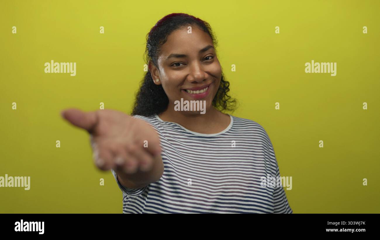Woman extends hand with open palm gesture in studio under bright yellow ...