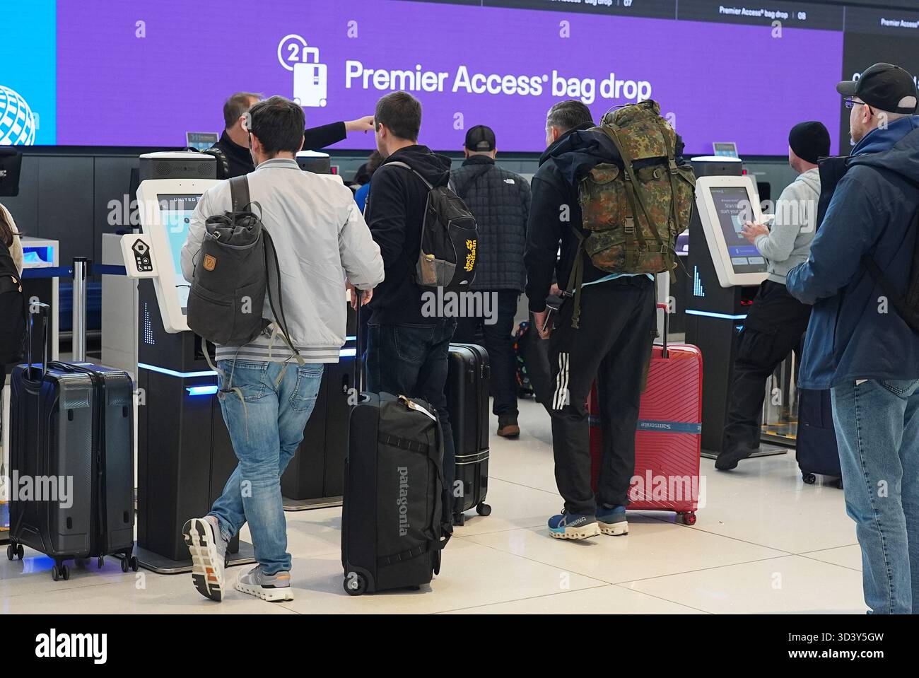 Travellers line up at self-check-in kiosks for flights on United ...