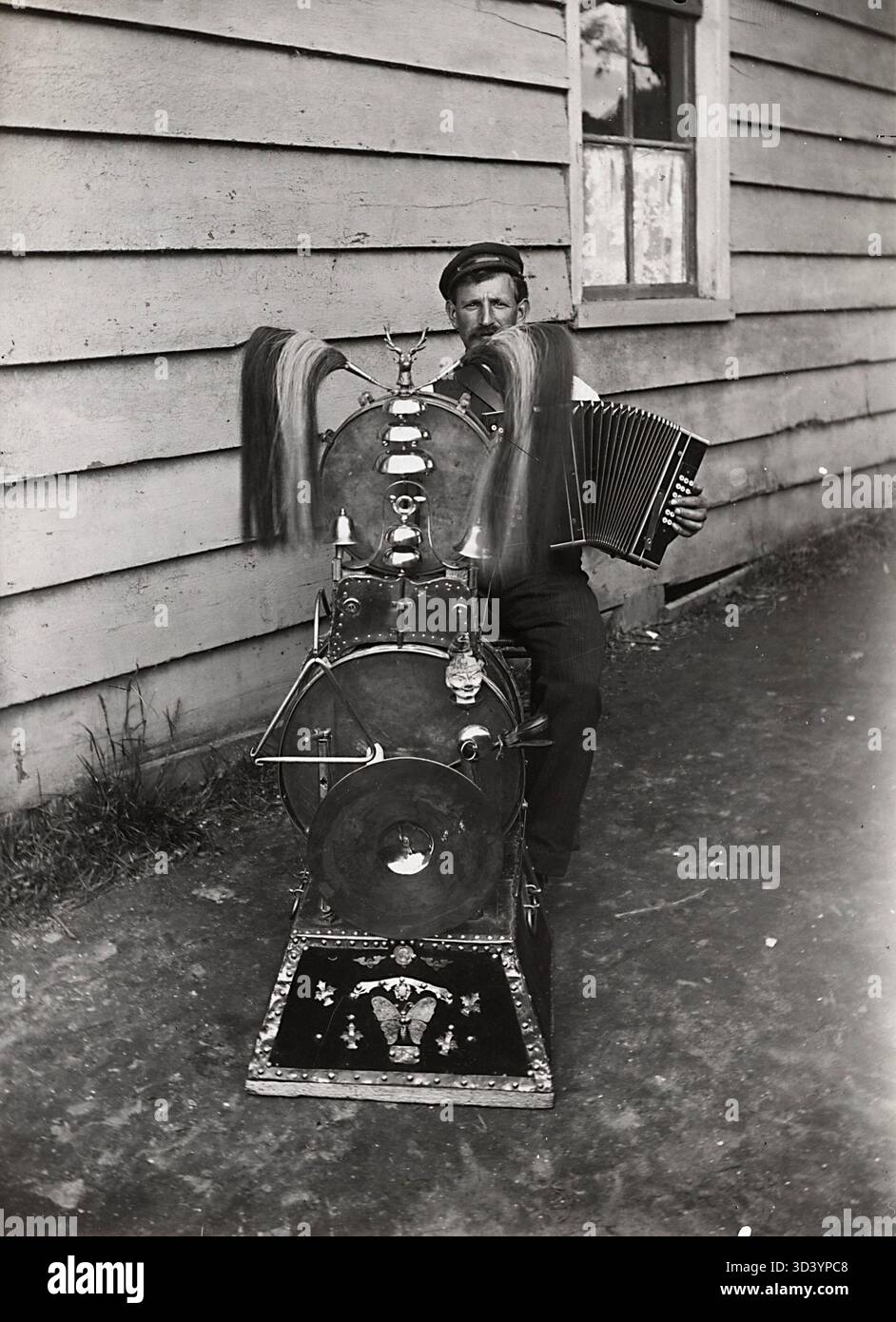 An invalid street musician plays an accordion, drums, bells, and a ...