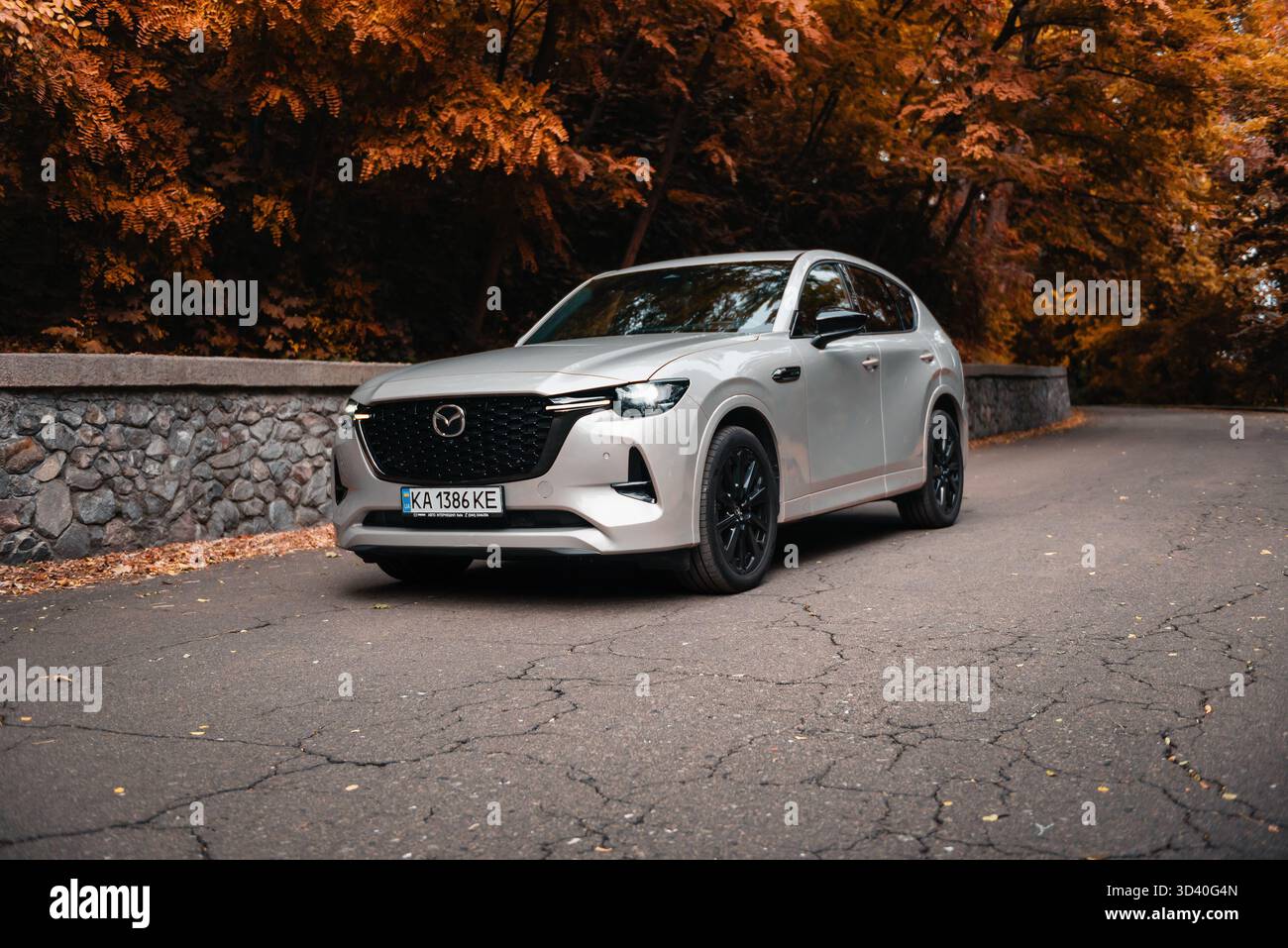 beige Mazda CX-60 in autumn forest. Three quarter front view of modern ...