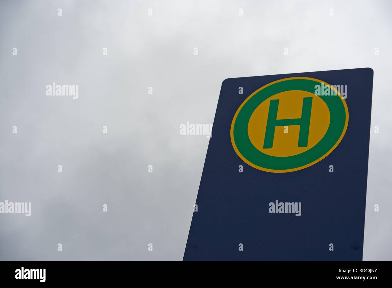 A yellow and green bus stop sign stands by the road and marks the place ...