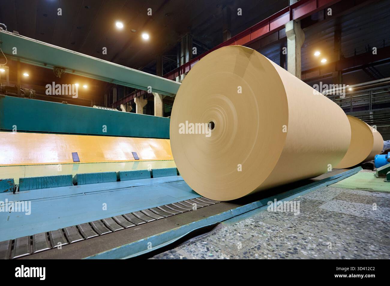 Large rolls of paper being processed at a busy paper mill in an ...