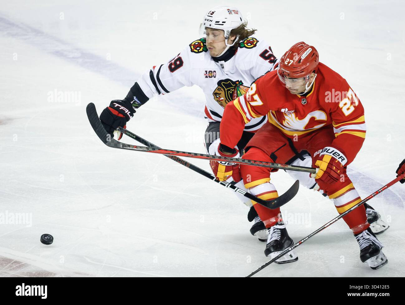 Chicago Blackhawks' Tyler Bertuzzi, left, is checked by Calgary Flames ...
