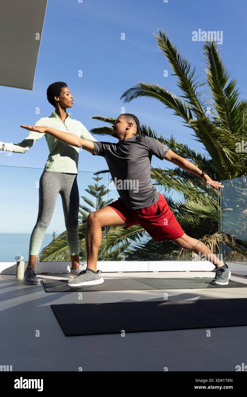 Diverse workout partners practicing yoga on outdoor terrace, with two ...