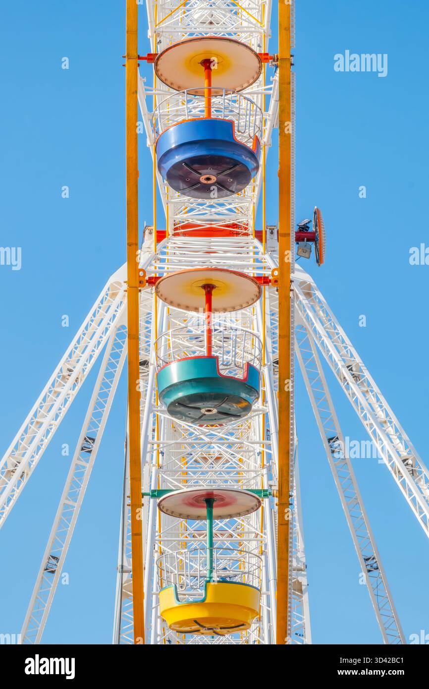 Vertical close-up of a Ferris wheel structure showing multiple brightly ...