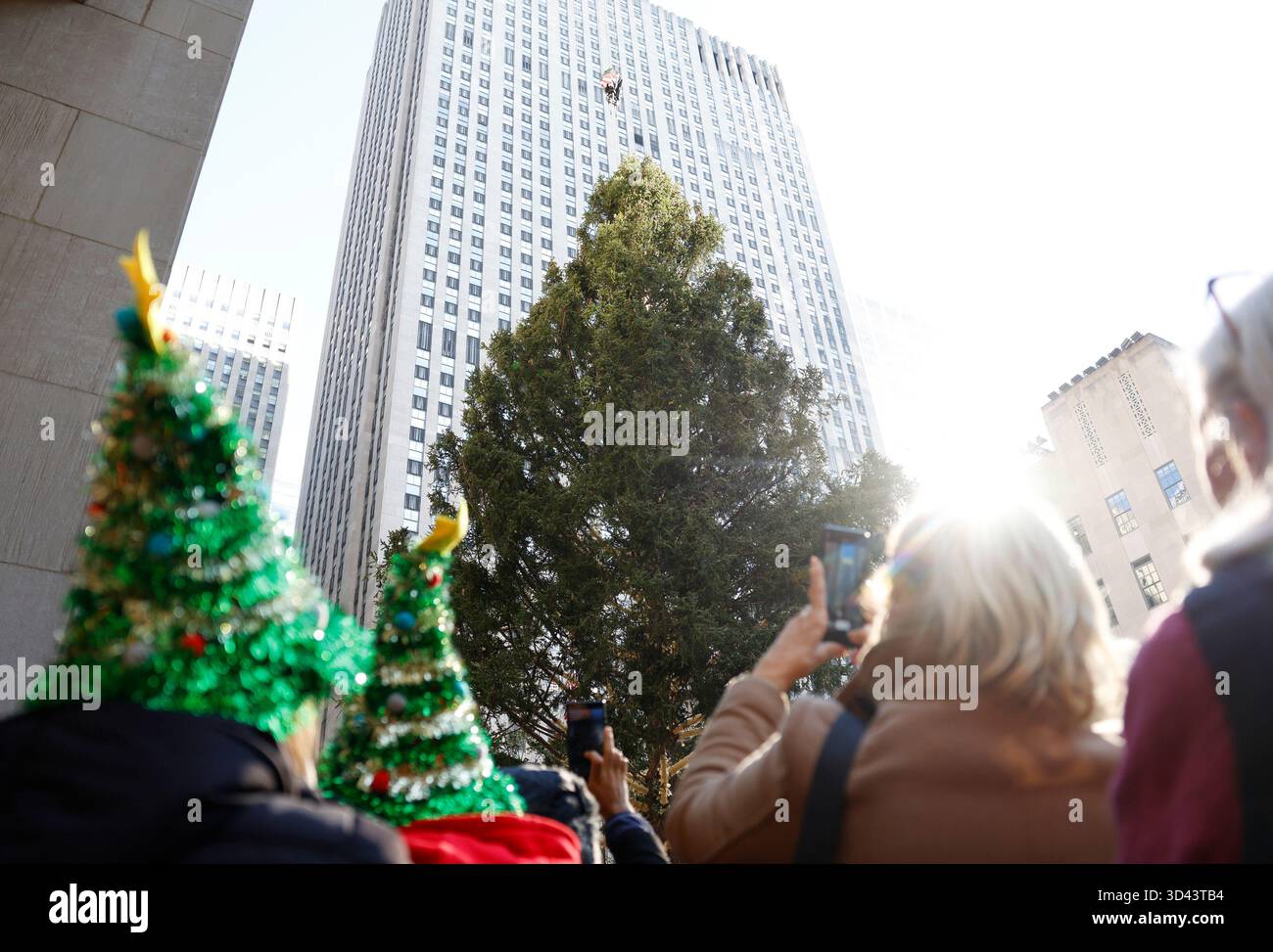 Spectators watch as workers lift into place by crane the Rockefeller ...
