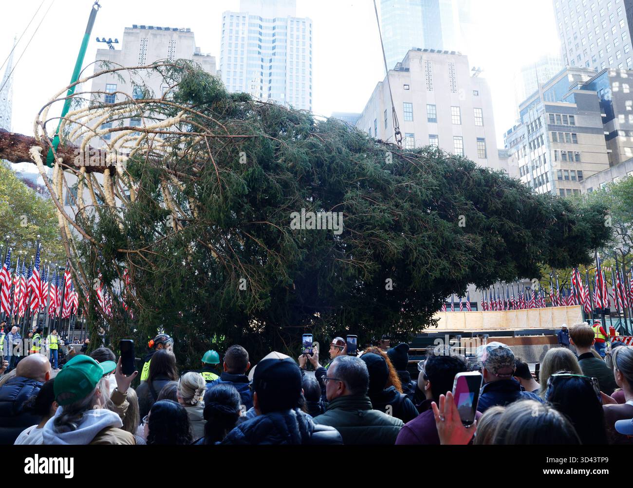 Spectators watch as workers lift into place by crane the Rockefeller ...