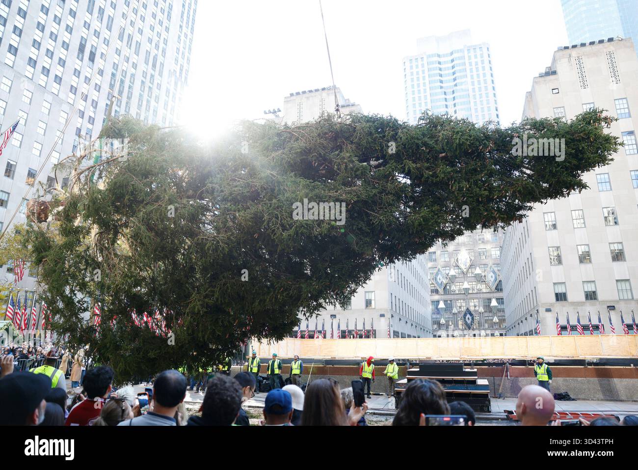 Spectators watch as workers lift into place by crane the Rockefeller ...