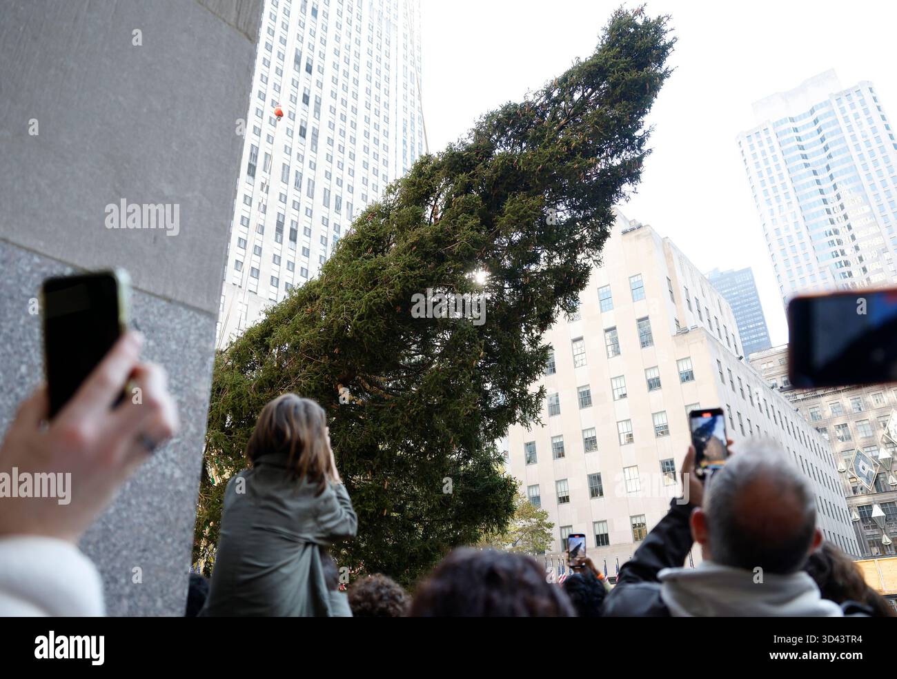 Spectators watch as workers lift into place by crane the Rockefeller ...