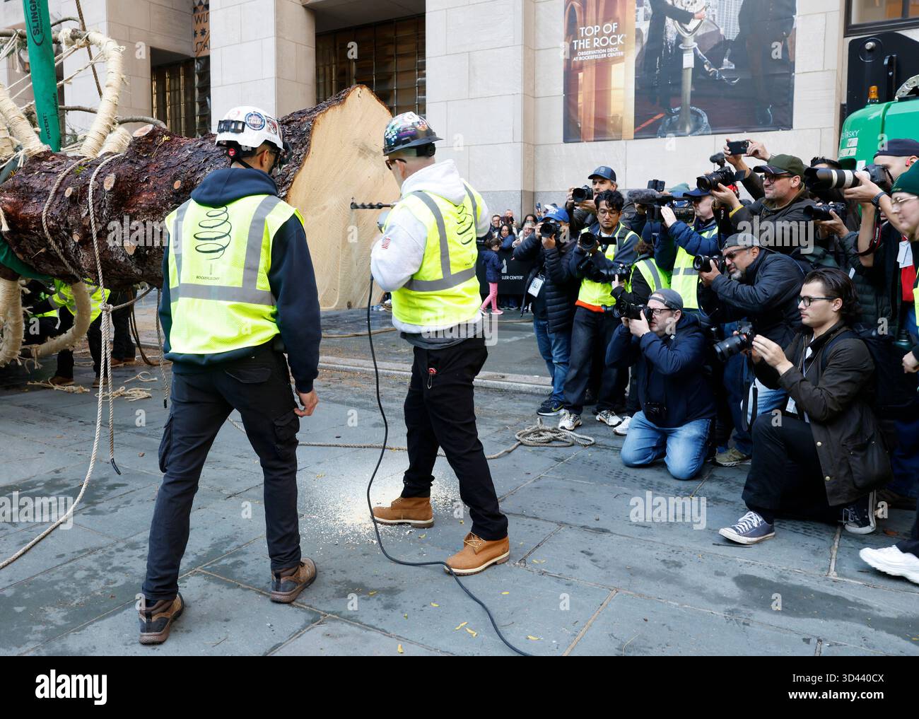 Photographers capture workers as they drill a hole to prepare for a ...