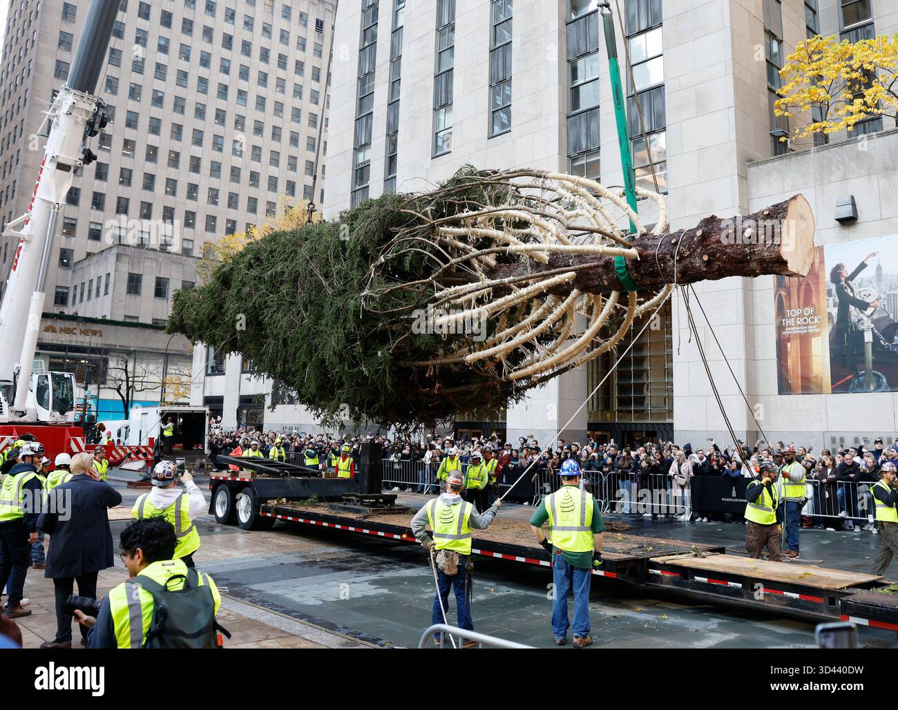 Spectators watch as workers prepare to lift into place by crane the ...