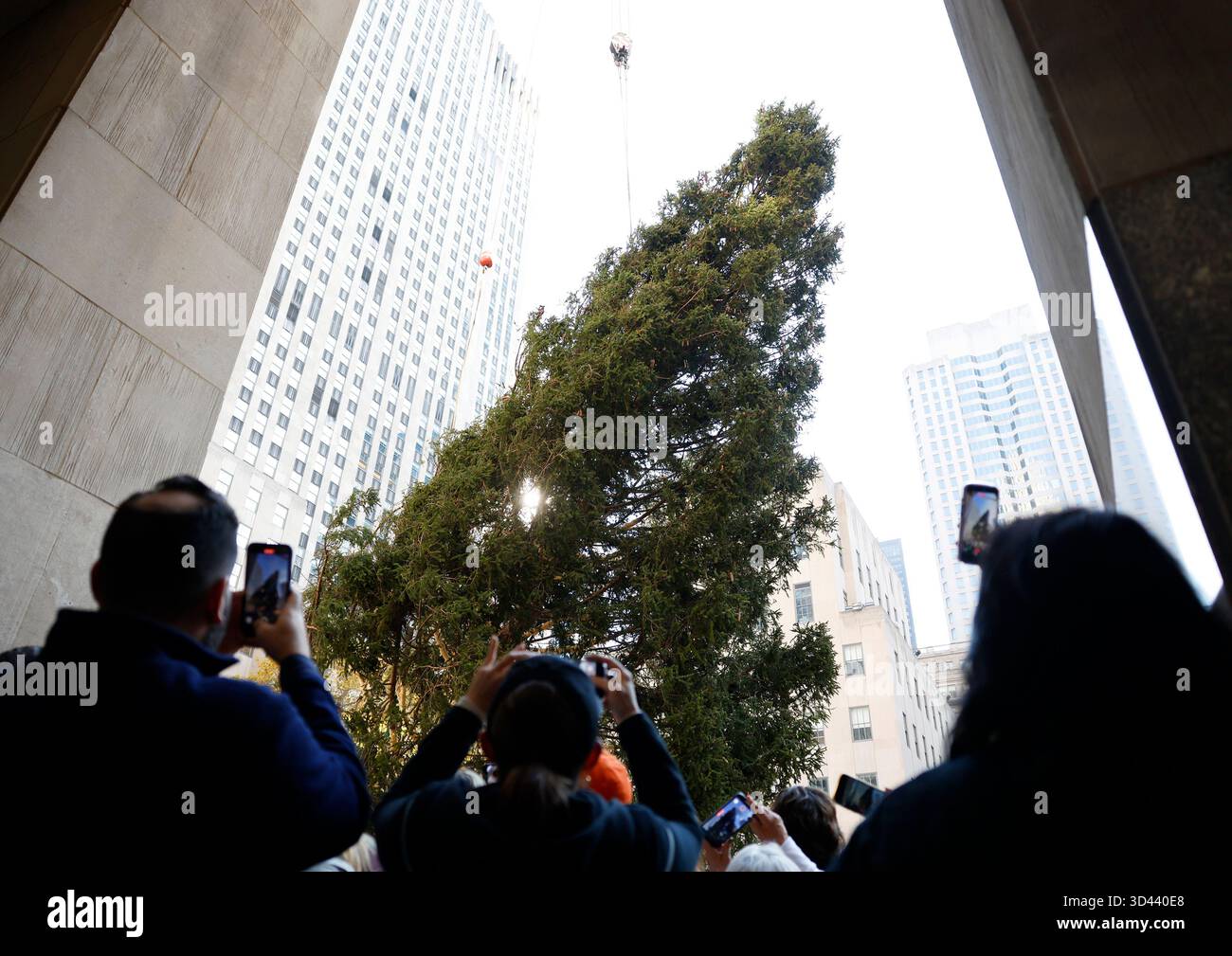 Spectators watch as workers lift into place by crane the Rockefeller ...