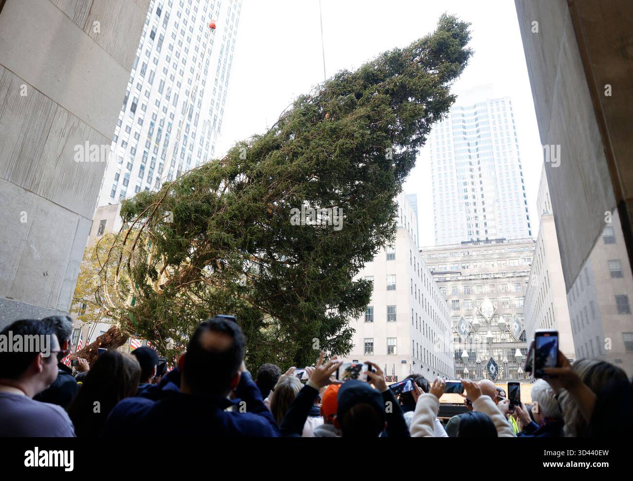Spectators watch as workers lift into place by crane the Rockefeller ...