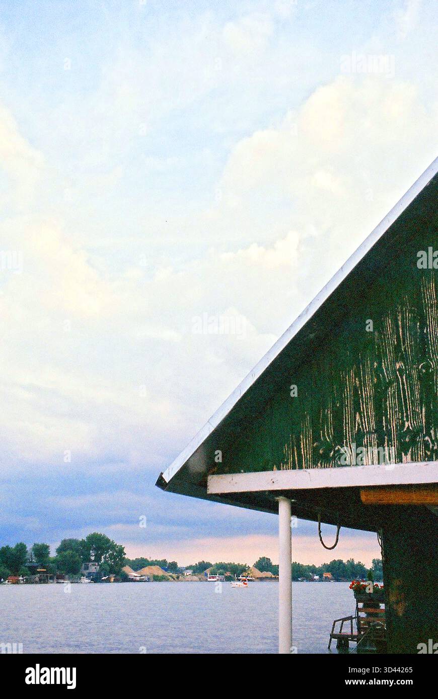 Edge of a metal roof on a raft made of green planks, cloudy sky, analog ...
