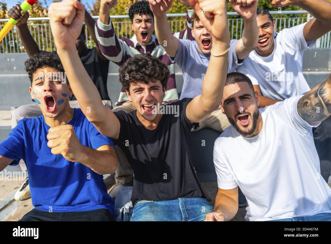 Excited multiethnic male friends cheering and raising fists in outdoor ...