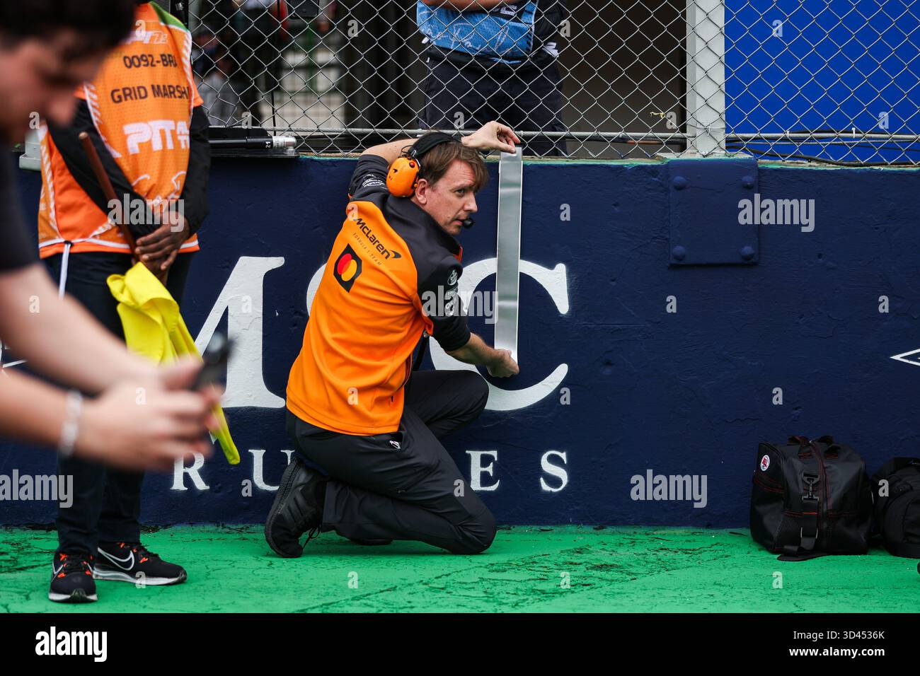 McLaren mechanic setting up a strip of tape to help Lando Norris ...