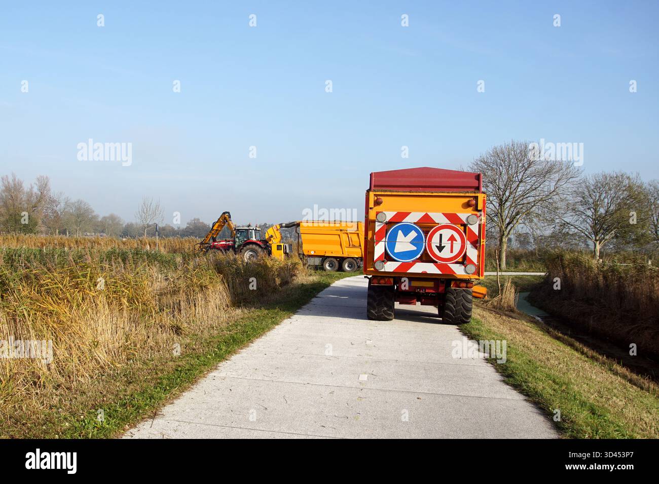 Tractors with mower and trailer for the mown grass. Verge along a cycle ...