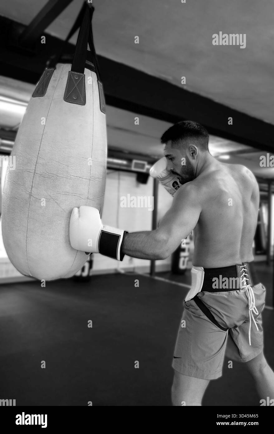 black and white photograph of a boxer punching the bag in the gym Stock ...