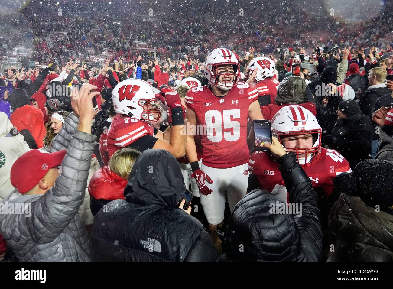 Wisconsin players celebrate as fans storm the field after an NCAA ...