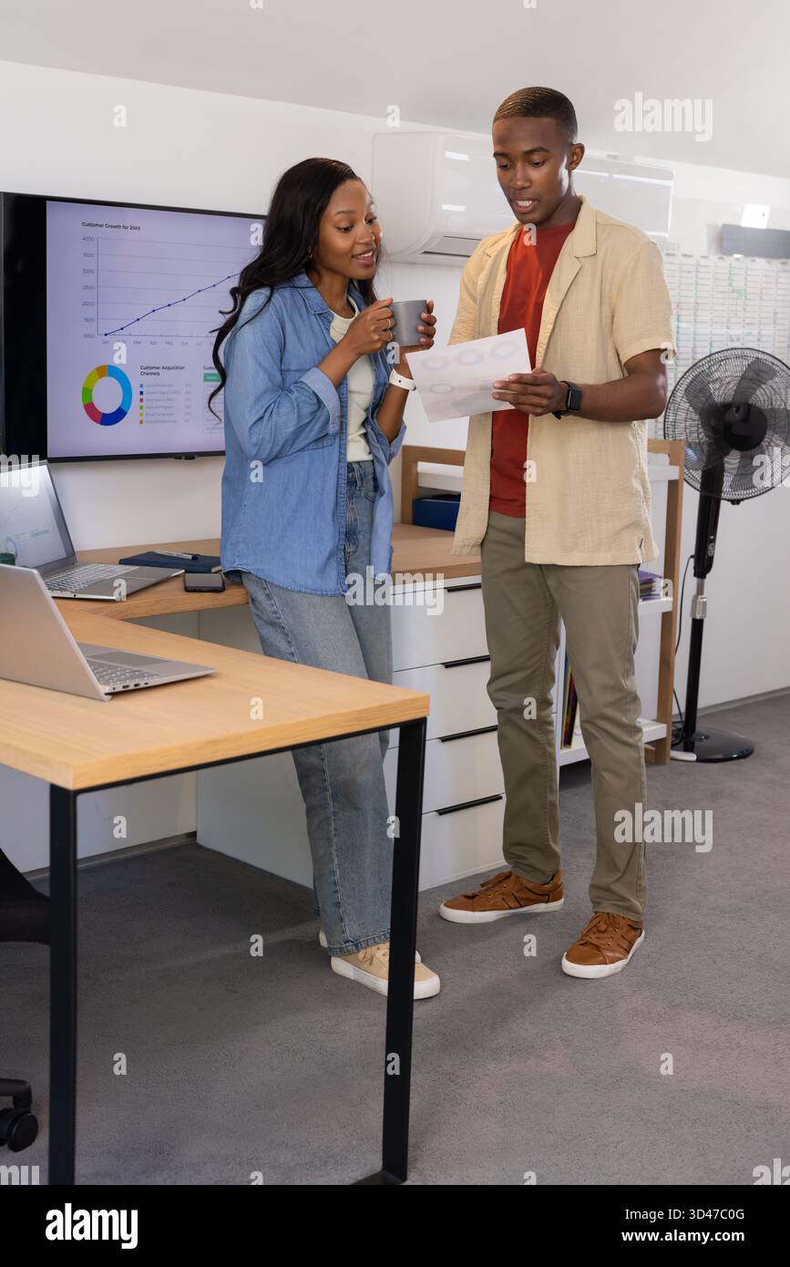 Discussing data African American coworkers using laptop and phone at ...