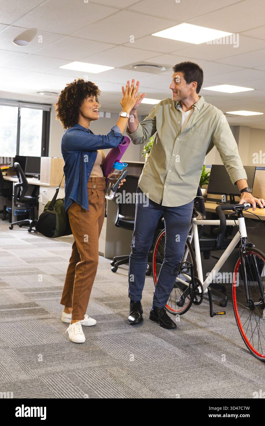 High-fiving diverse coworkers celebrating work milestone in modern ...