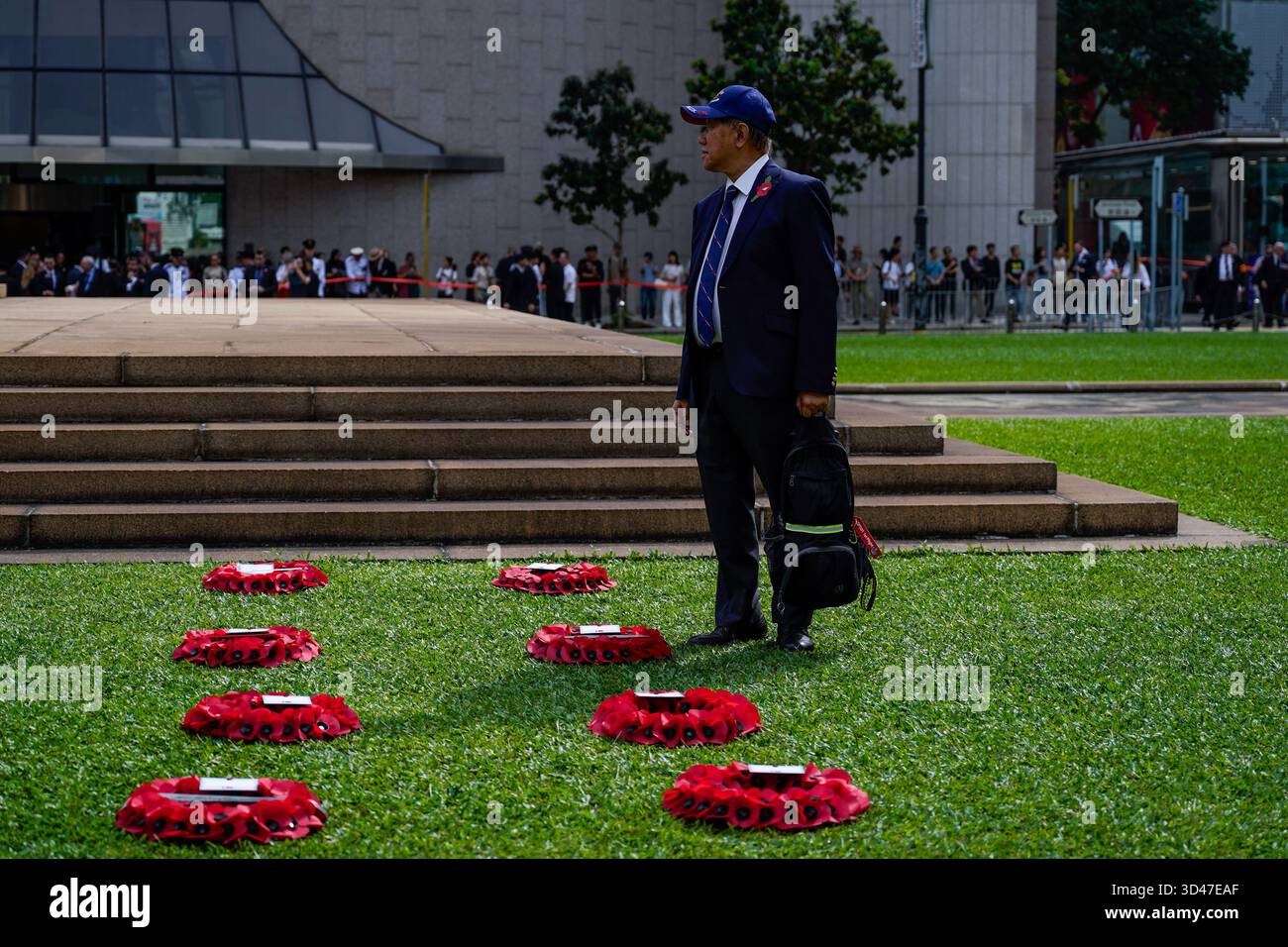 A man standing next to Remembrance Day flower circle placed on the ...