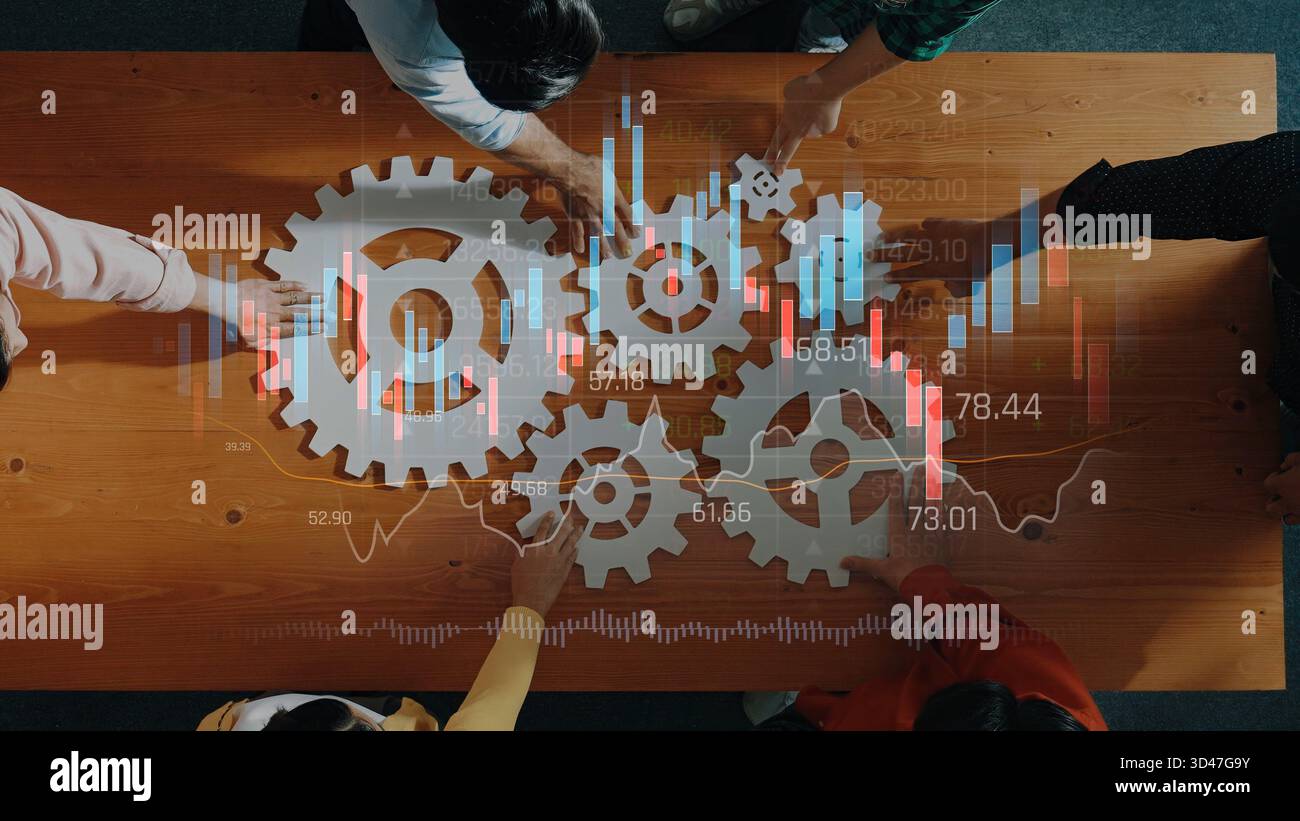 A group of professionals collaborates around a table featuring gears ...
