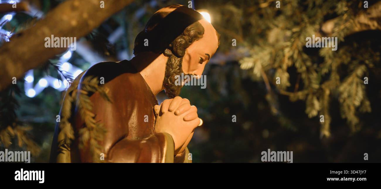 Close-up of Joseph's figurine praying with his hands clasped together ...