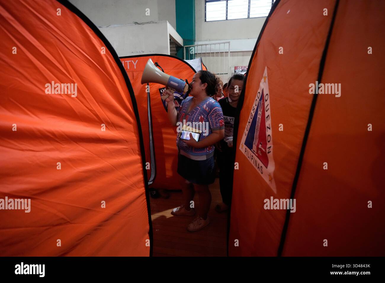 A worker uses a megaphone to call on residents at an evacuation center ...