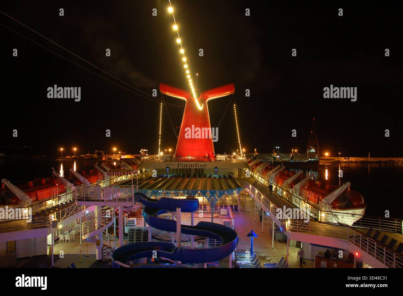 Night view of a cruise ship deck with illuminated water slide, red ...
