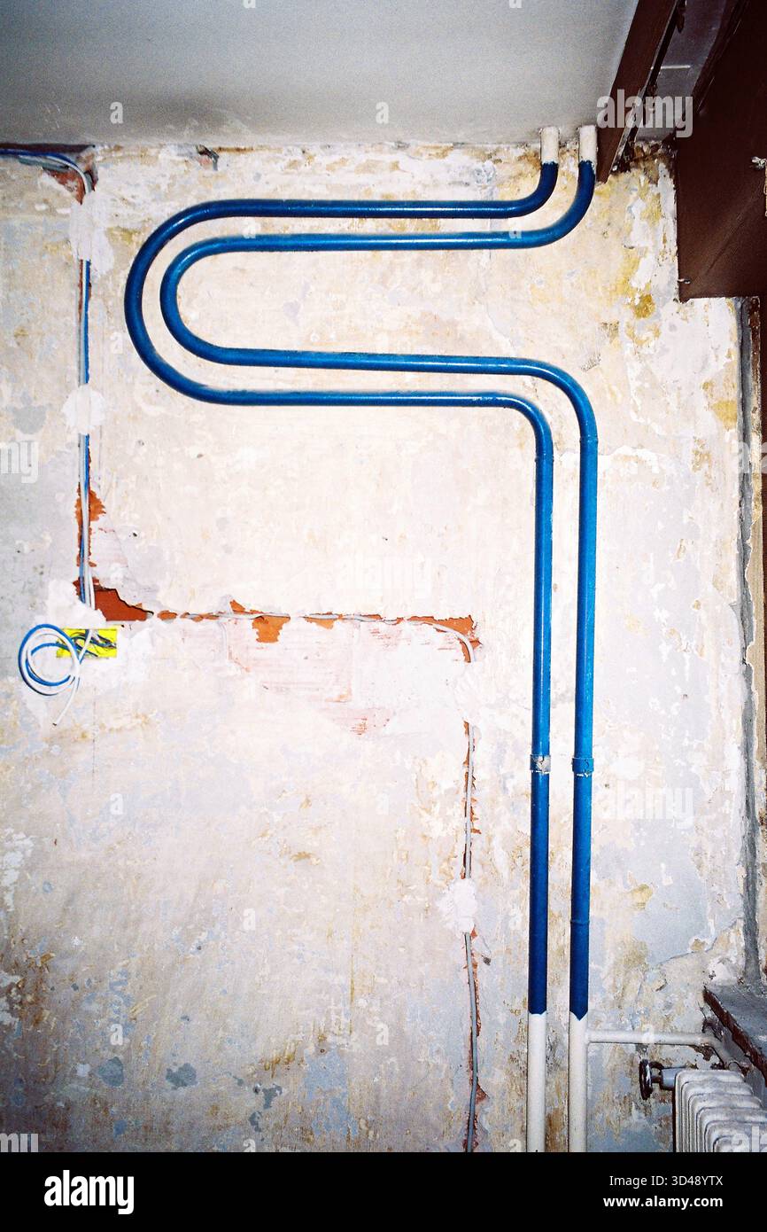 Wall texture with old paint layers, exposed channels, blue heating ...