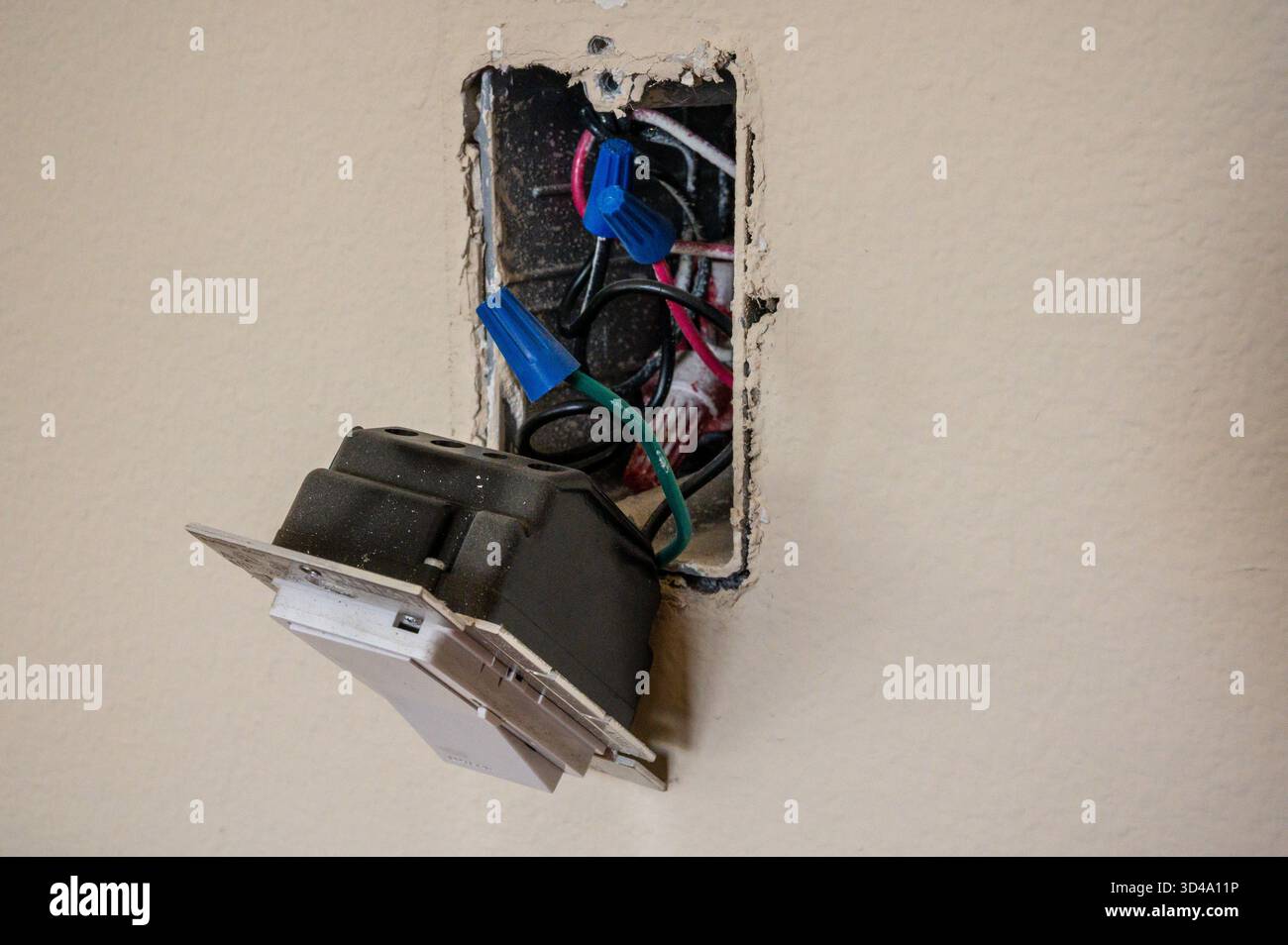 Closeup of a retrofit smart lighting dimmer being installed in a wall ...