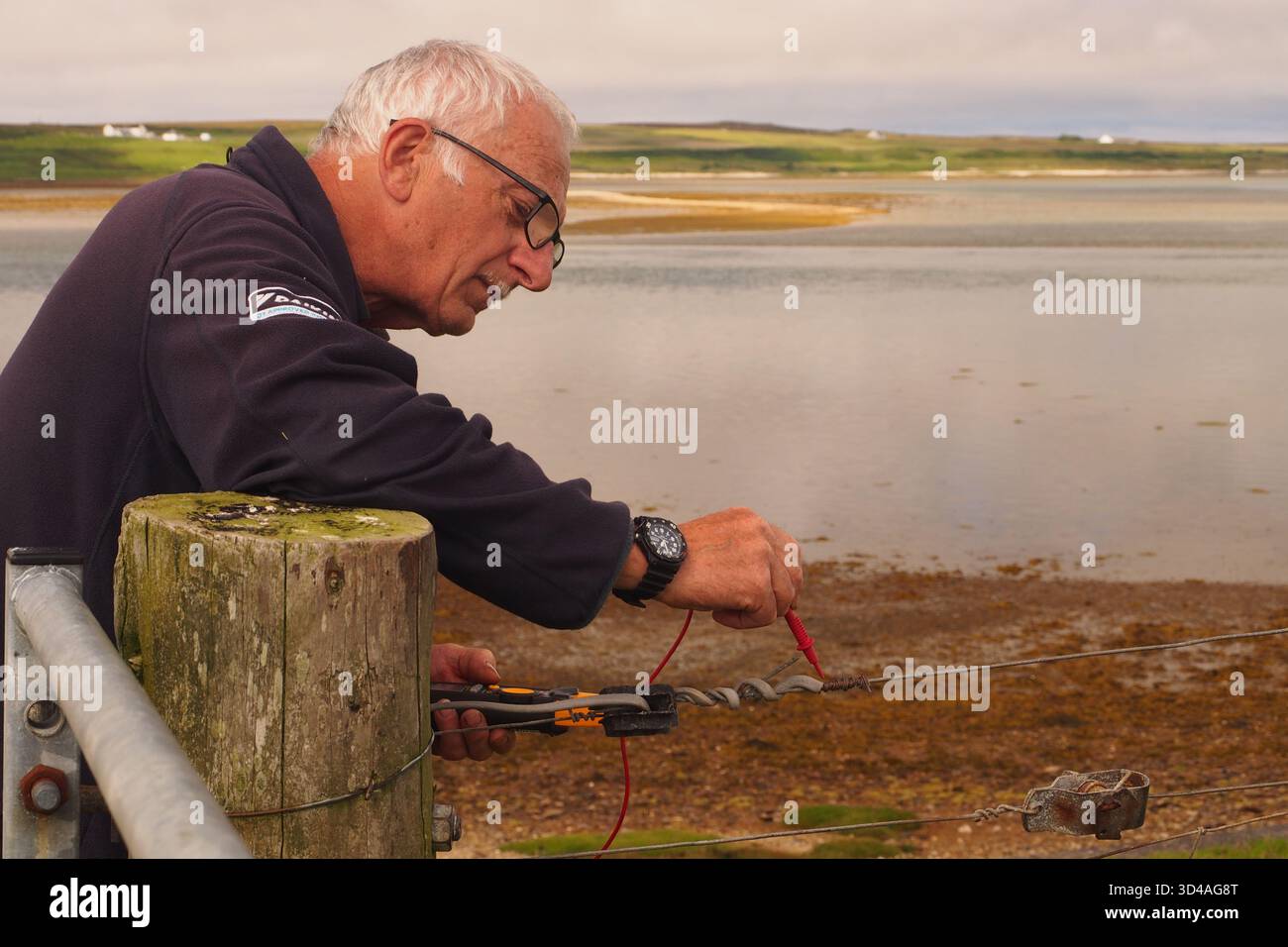 A man testing the voltage on an electric fence out in the wild ...