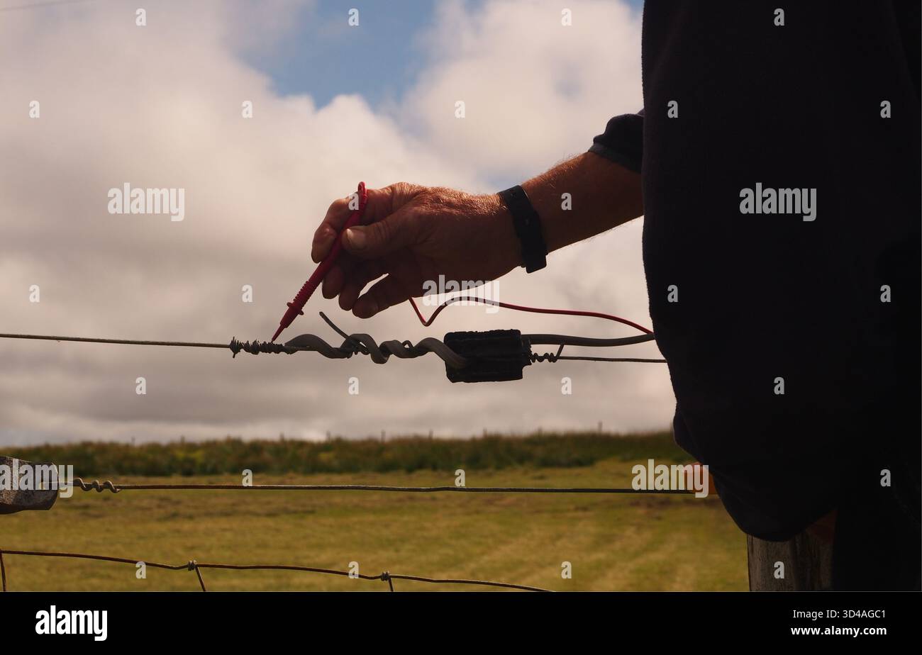 A man testing the voltage on an electric fence out in the wild ...