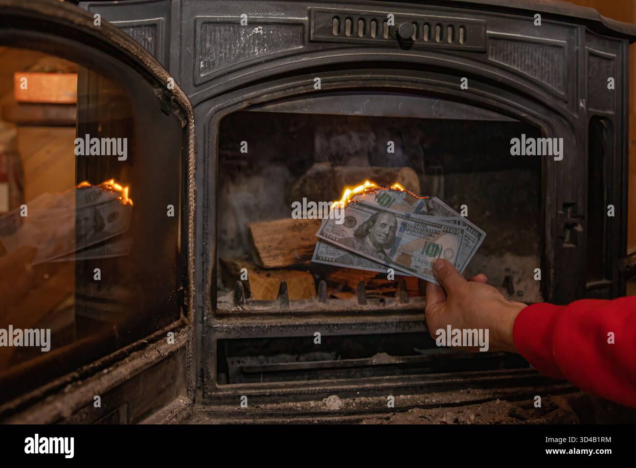 Burning fake US dollar bills inside a cast iron fireplace as concept of ...