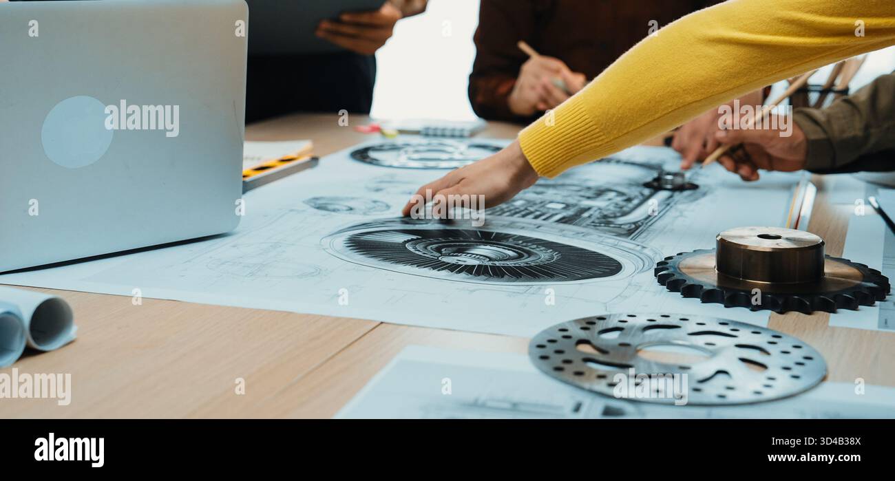 A diverse team collaborates around a table filled with technical ...