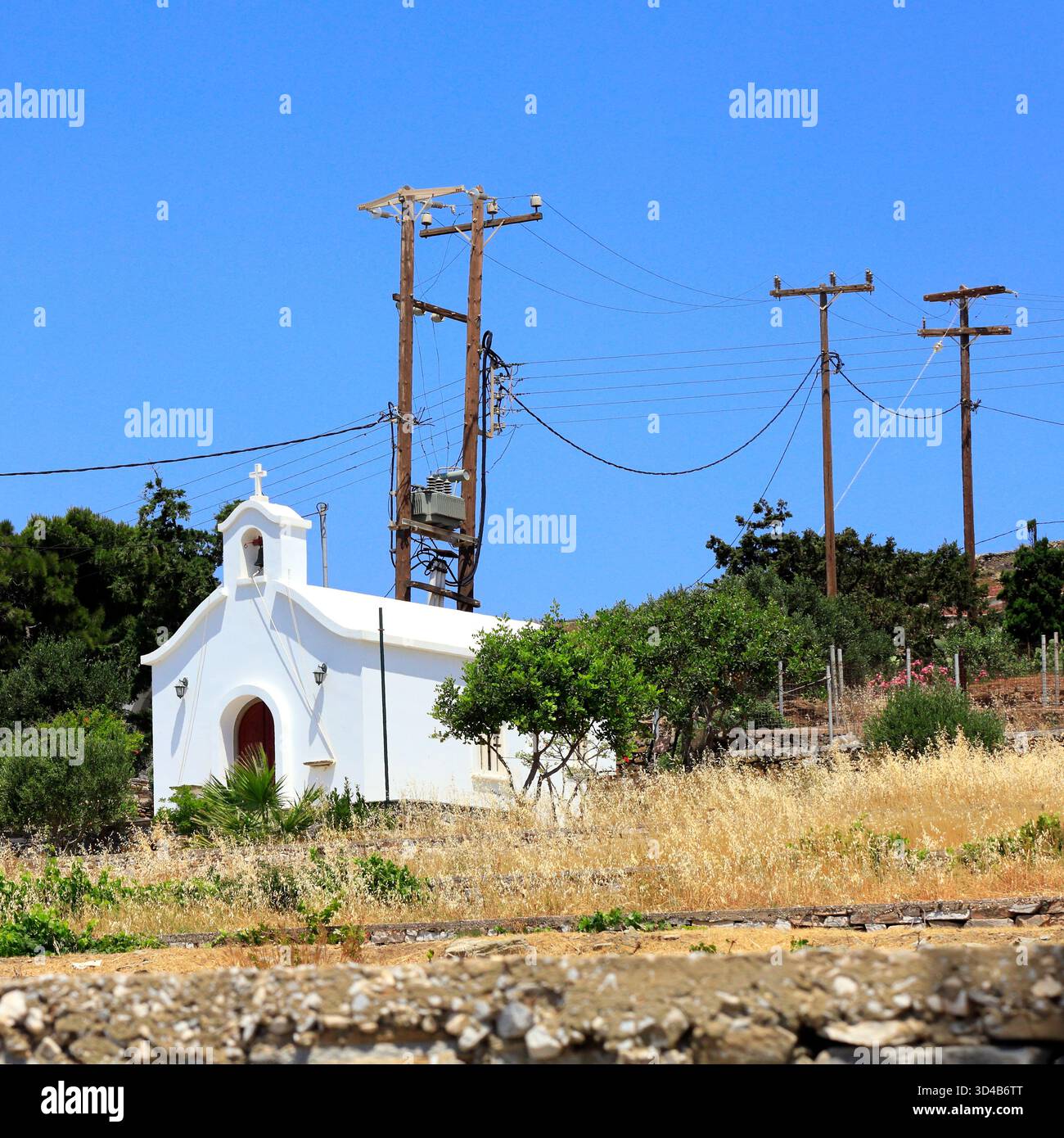 Small whitewashed church surrounded by crooked electricity pylons and ...