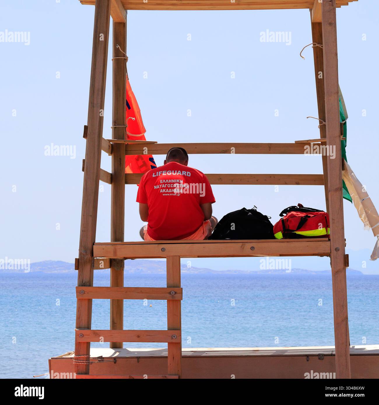 Lifeguard on duty on a lookout platform on a quiet beach, early summer ...