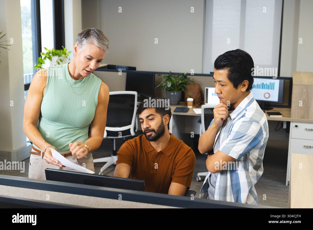 Diverse coworkers reviewing report at desk in modern office, with ...