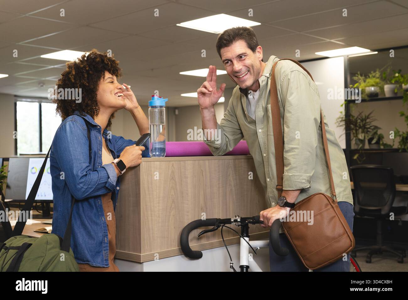 Talking Diverse coworkers standing at open-plan office workspace, with ...
