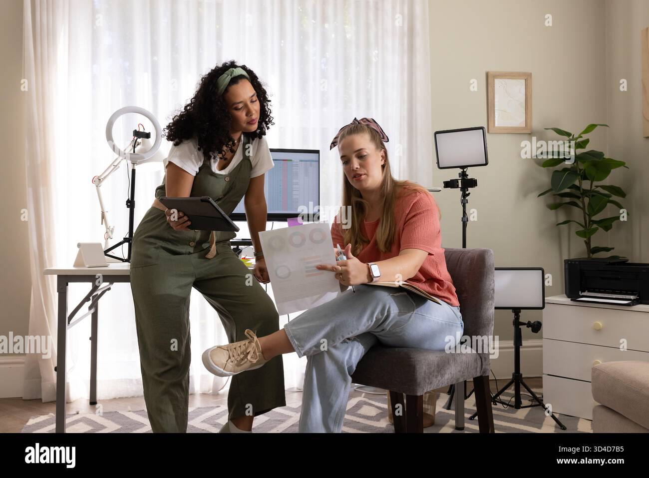 Working Diverse female coworkers reviewing chart at home office, with ...
