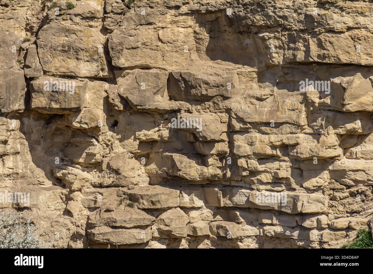 Bright sunlight highlights the rugged textures of a rock formation ...