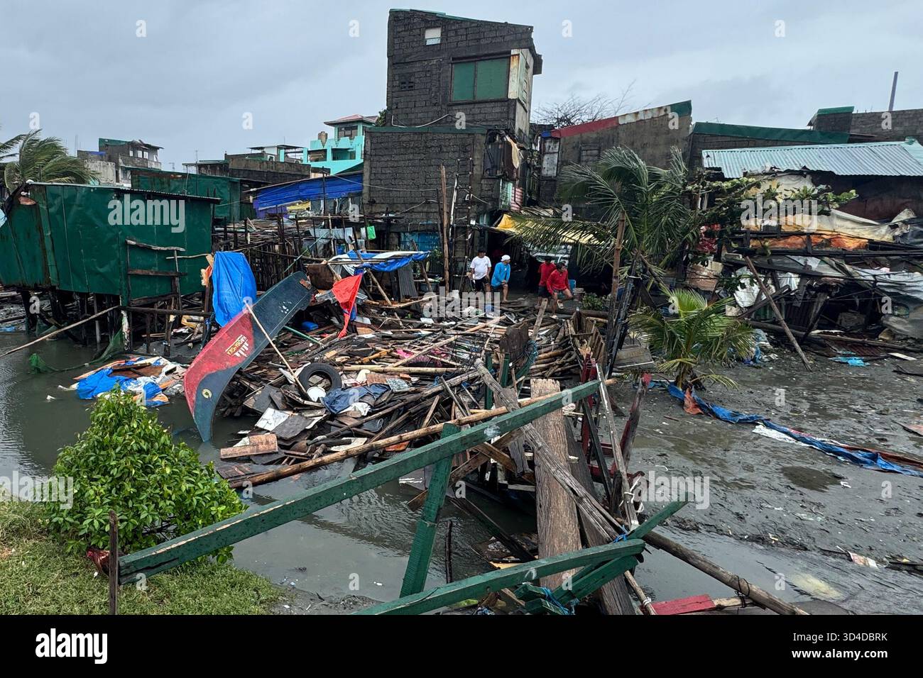 Residents stand beside a damaged house and toppled bridge due to ...