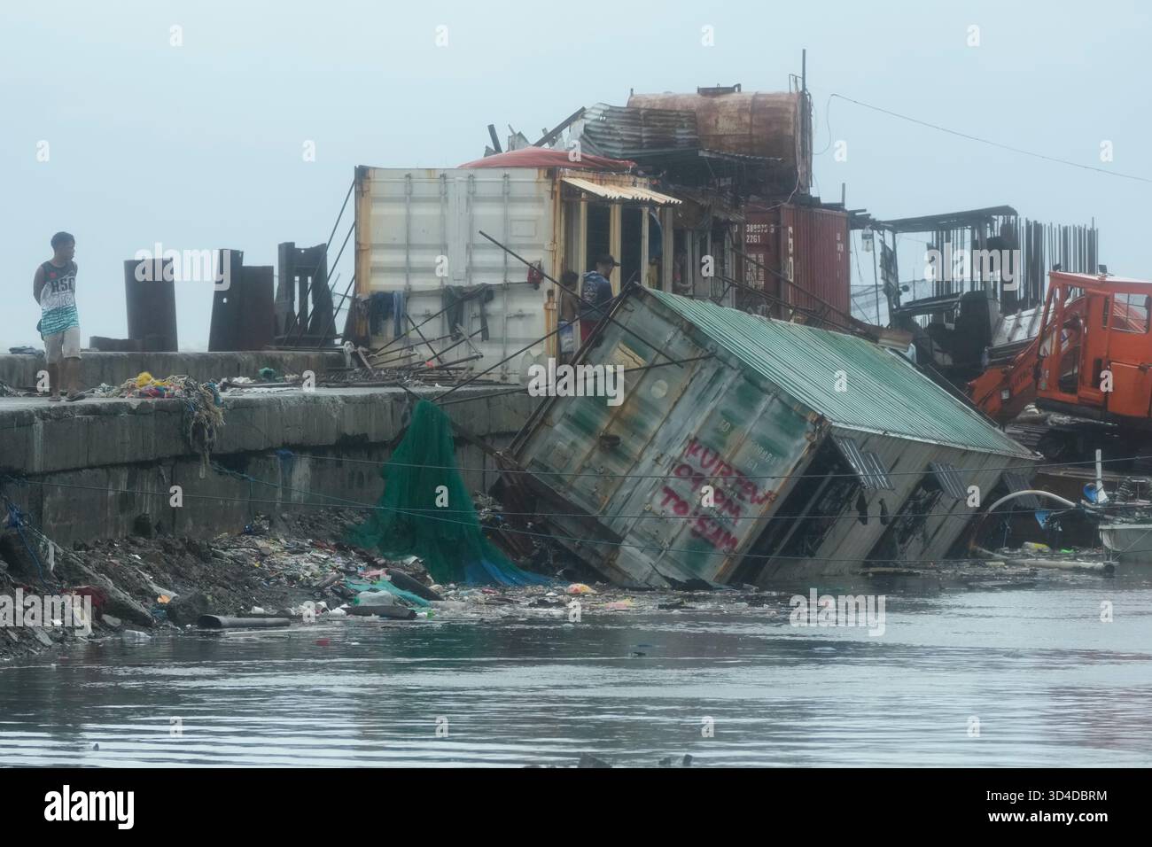 A man walks beside a container van that was toppled due to strong winds ...