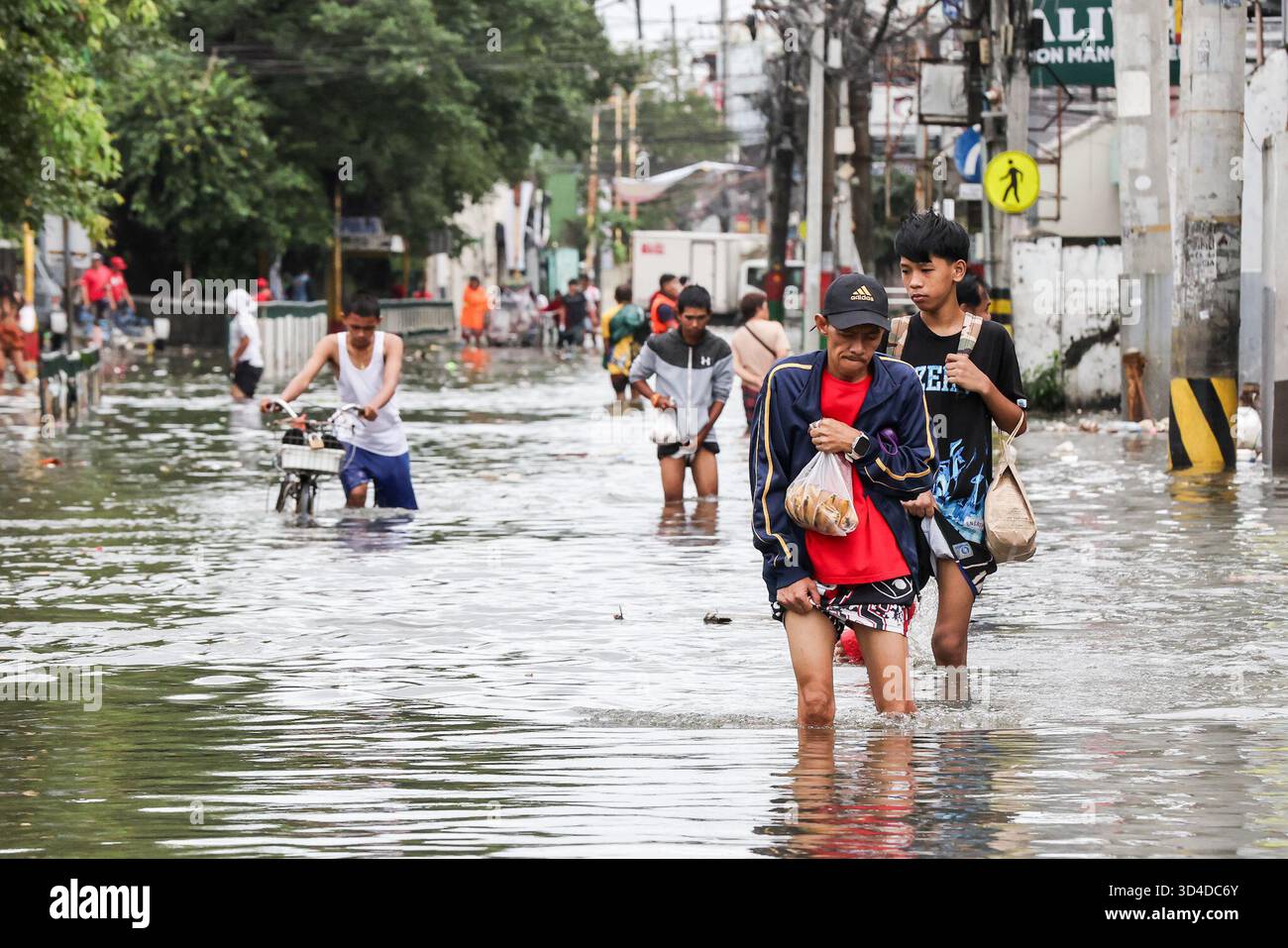 Navotas City, Philippines. 10th Nov, 2025. Residents wade through flood ...