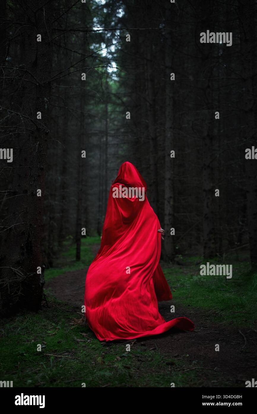 figure draped in a striking red cloak navigates a shadowy forest ...