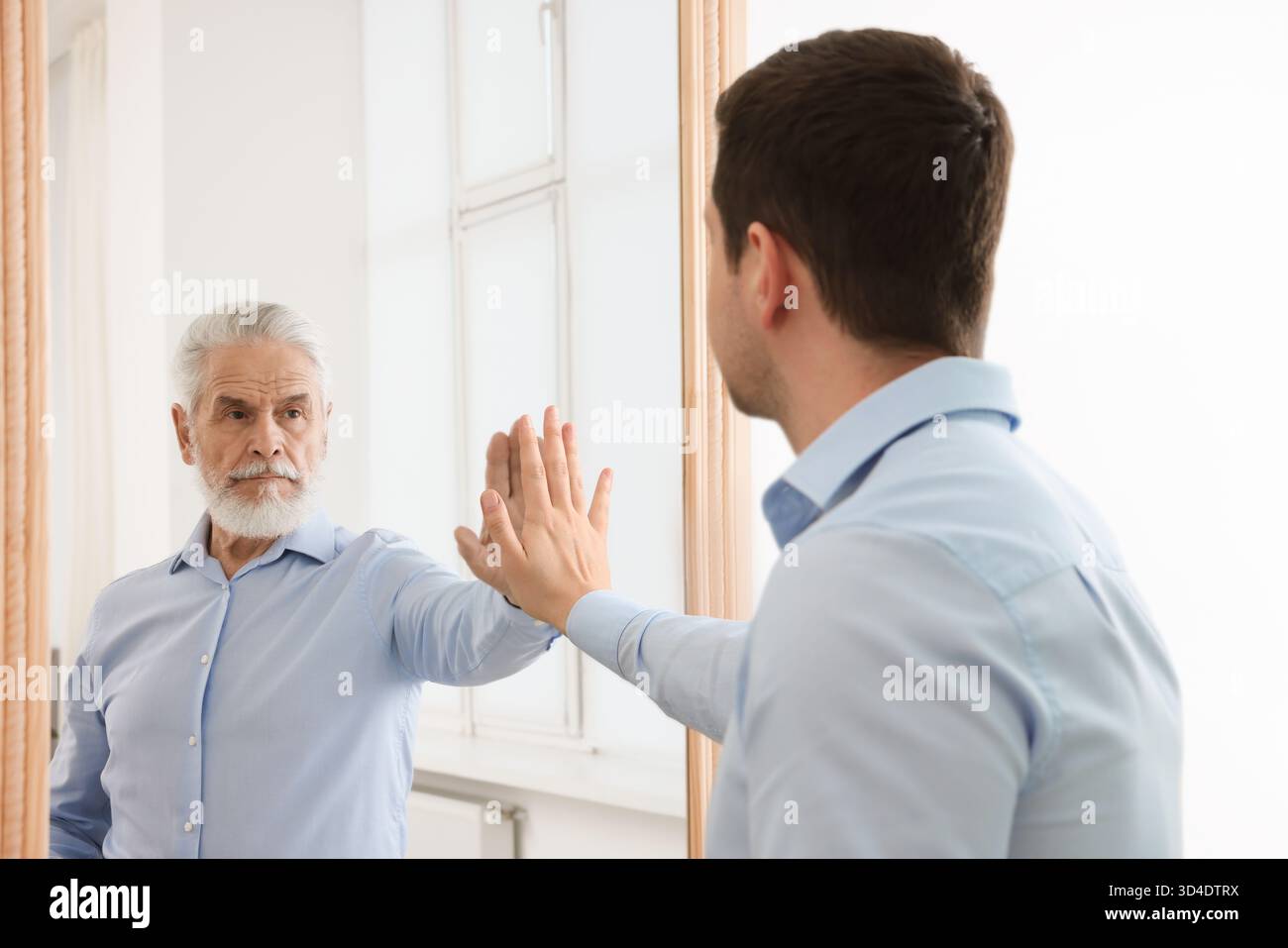 Young man seeing himself in mirror as senior man. Concept of past and ...