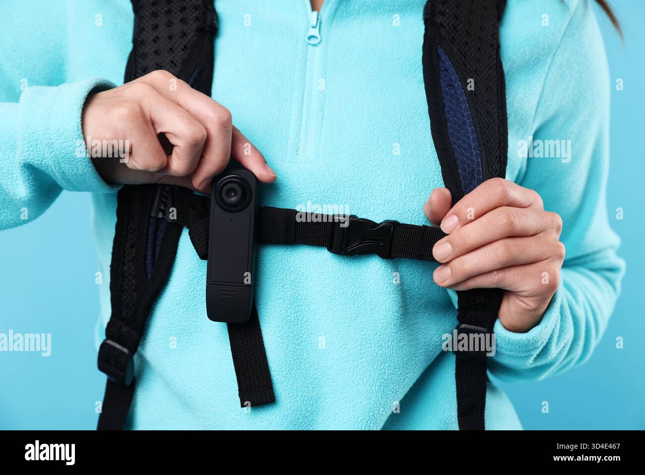 Tourist with hidden spy camera and backpack on light blue background ...