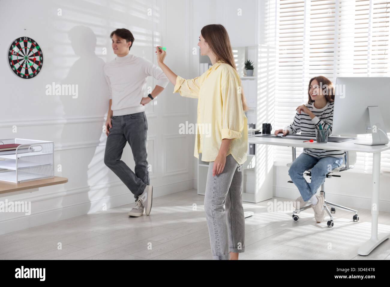 Woman playing darts and her colleagues in office Stock Photo - Alamy