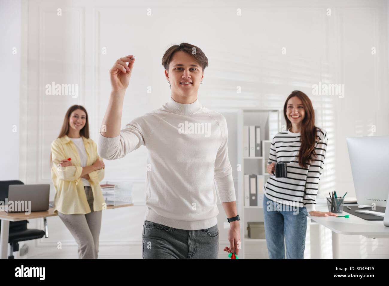 Man playing darts and his colleagues in office Stock Photo - Alamy